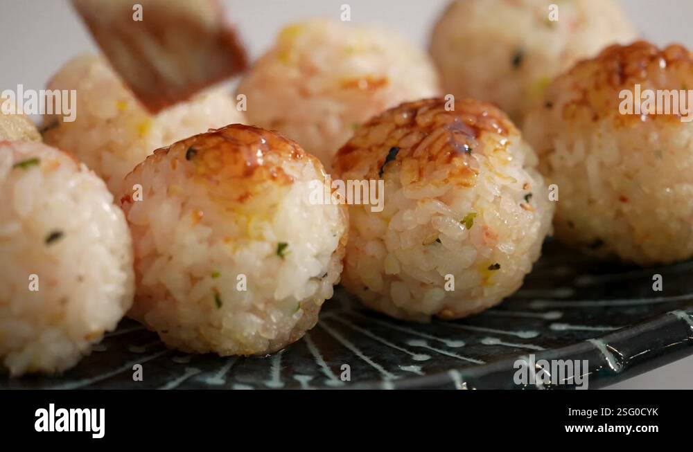 Brush sweet soy yaki sauce and mayonnaise on small round rice ball in ...