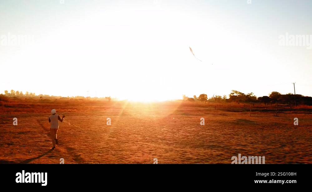 Panning Shot Of Man Flying Kite And Running In Field During Sunset ...
