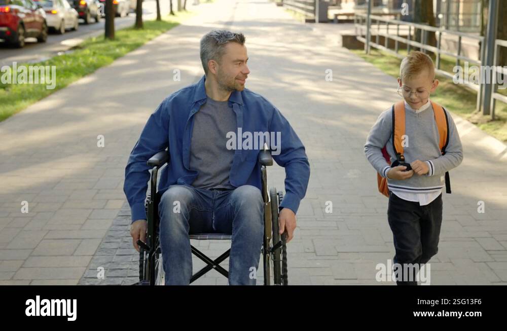 A disabled father in a wheelchair and his son talk about school and how ...