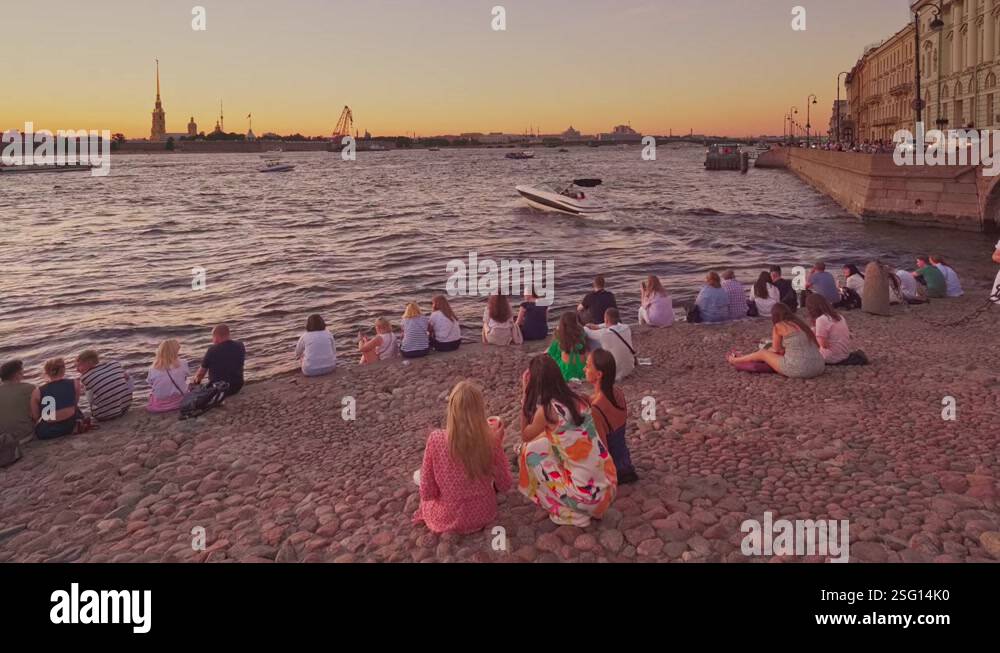4k, tourists sit on the stone pavement of the Neva river embankment ...
