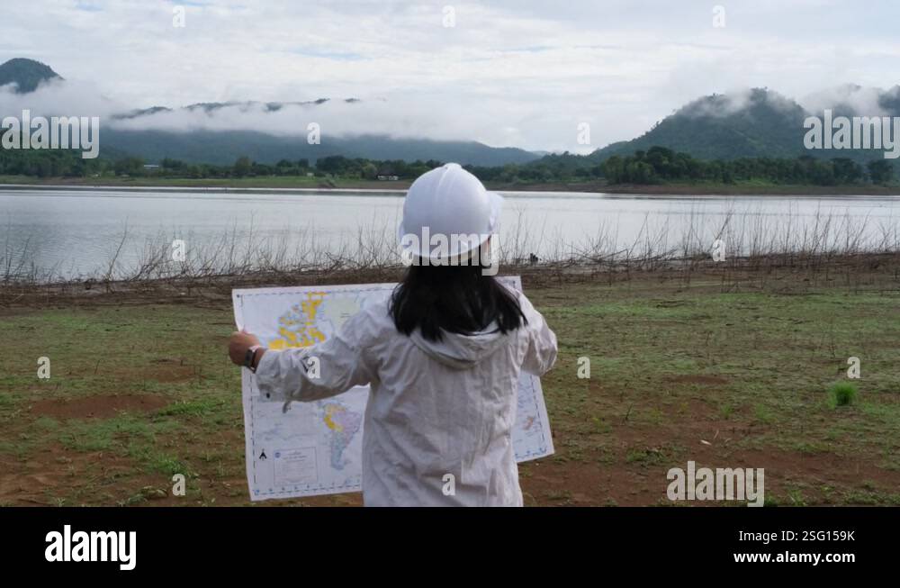 Engineering holding a riverbank map to develop a hydroelectric dam ...