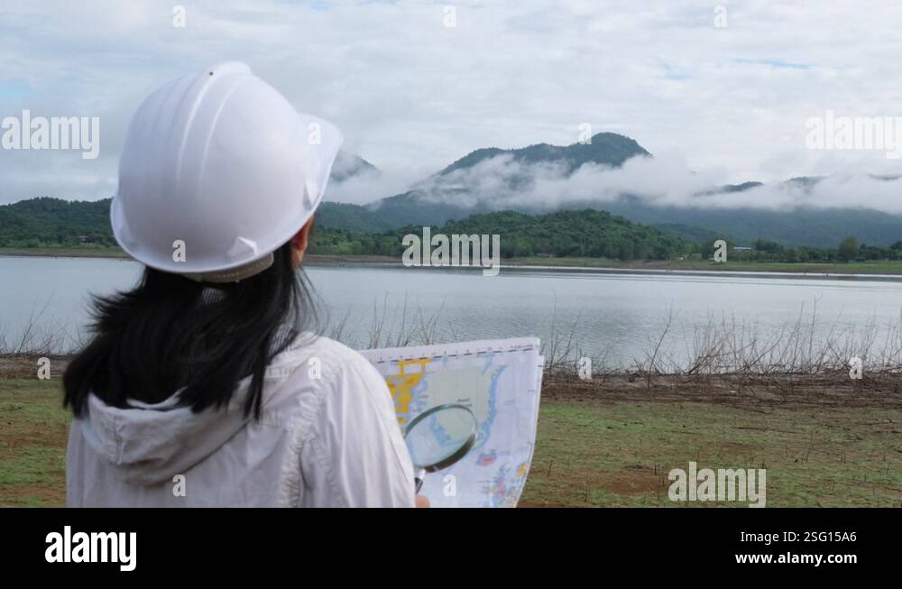 Engineering holding a riverbank map to develop a hydroelectric dam ...