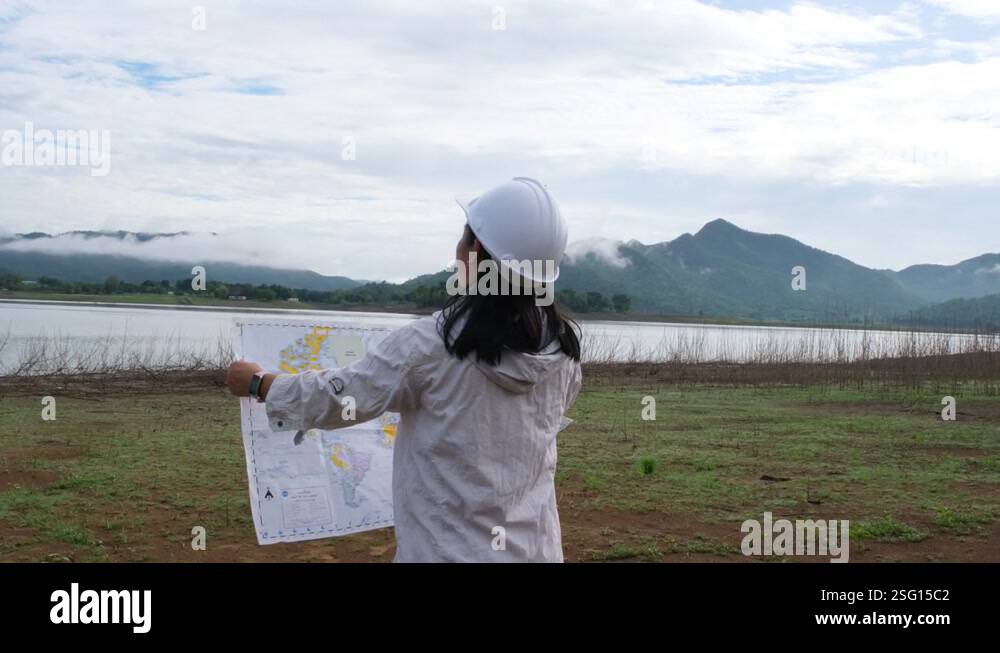 Engineering holding a riverbank map to develop a hydroelectric dam ...