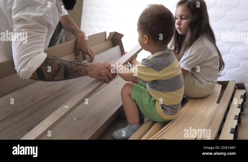 Dad, daughter and son open the boxes for the future bed in the kids ...