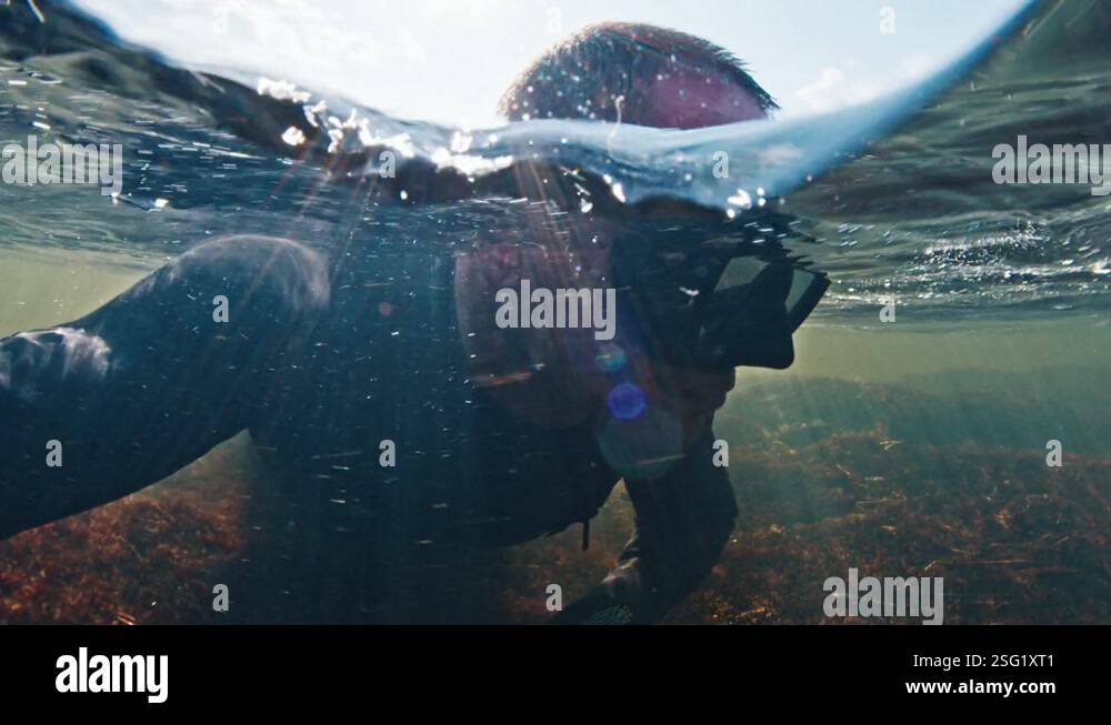 Diver with mask swims in the shallow rapid river and watches around ...