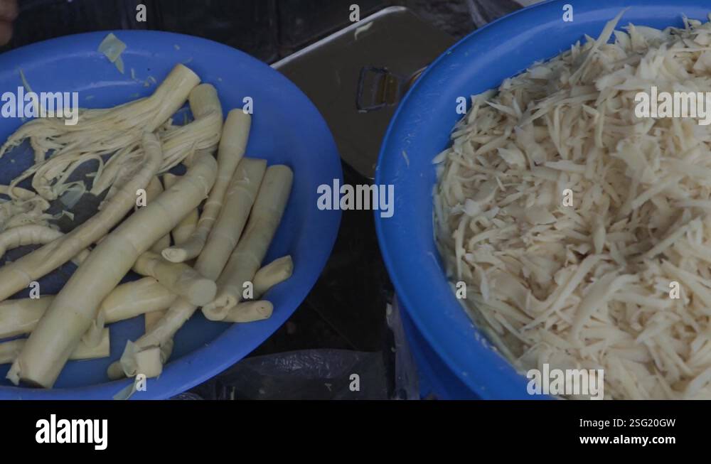 Panning of food vendor shredding bamboo shoots with knife for ...
