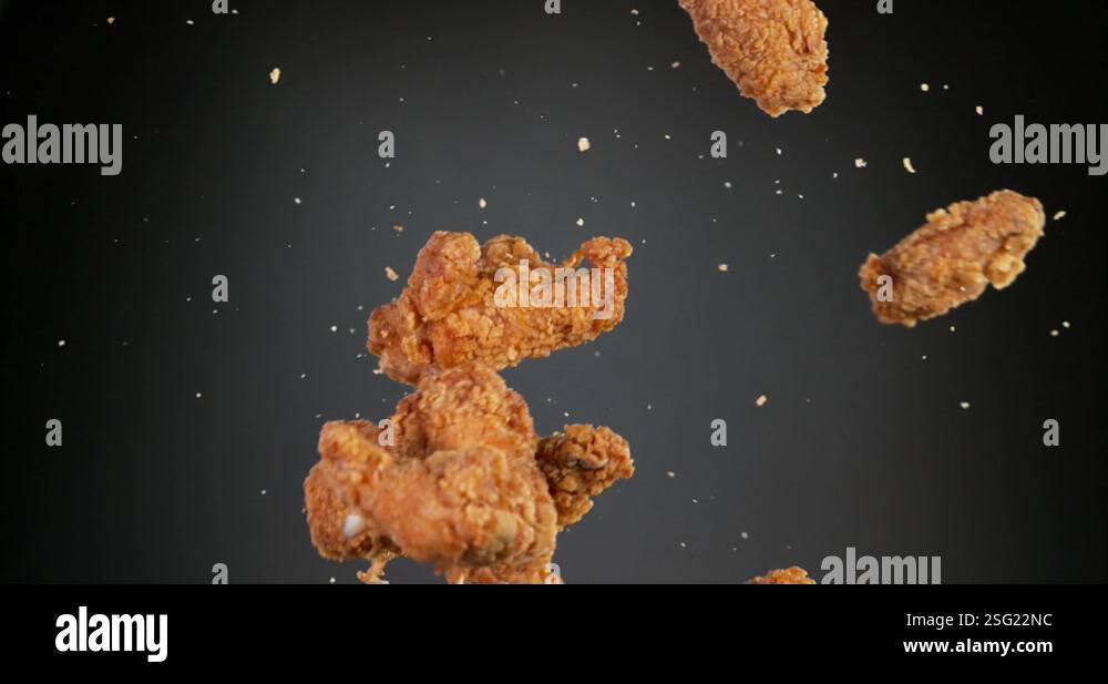 Super slow motion of flying fried chicken pieces hitting in the air ...