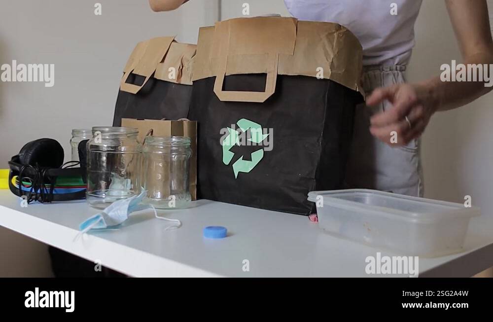 Sorting garbage at home for recycling. A woman puts used things into ...