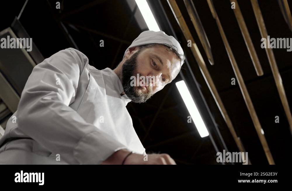 View from below on Caucasian handsome male baker in apron and hat ...