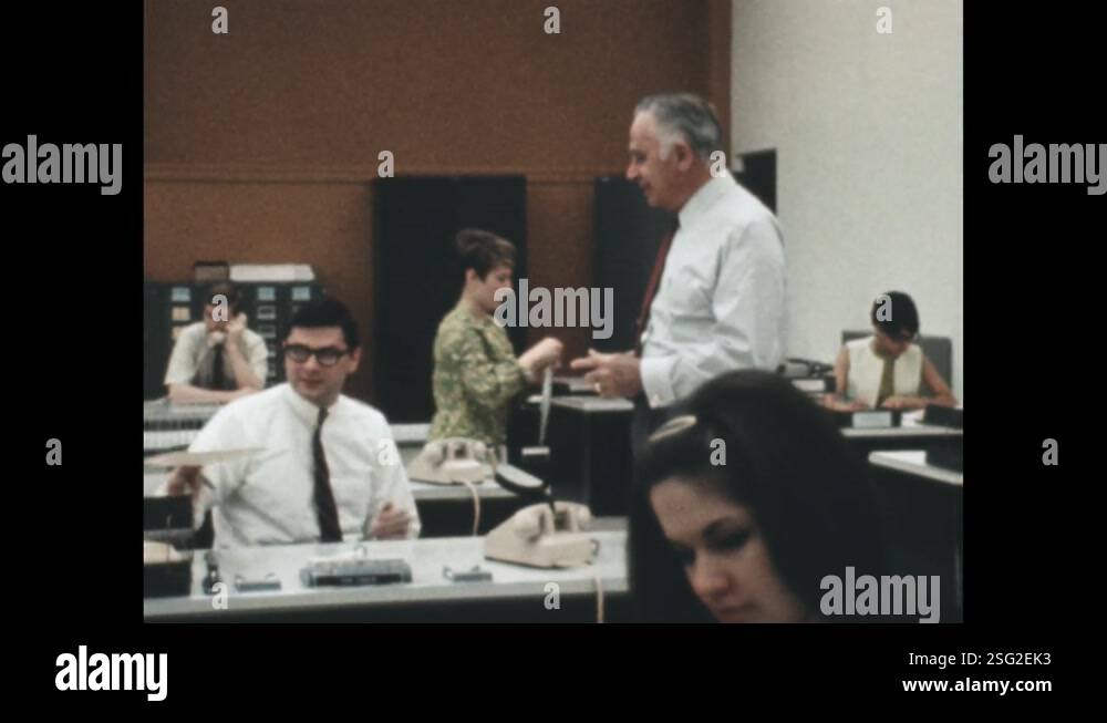 1960s: Open office, people sit at desks, woman types on typewriter ...