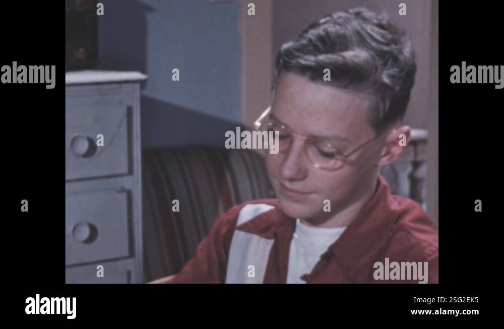 1950s: Boy shaking his head in frustration. Boy stands up from his desk ...