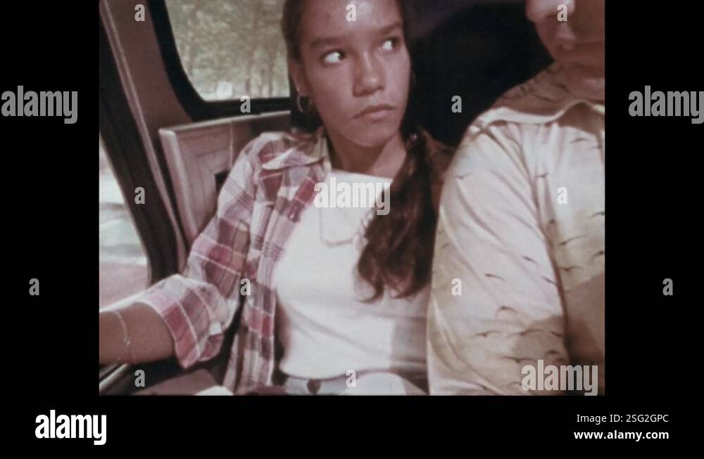 1980s: Young woman tries to study on bumpy bus ride. Young man lays on ...