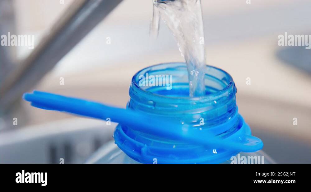 Water pours from faucet into plastic bottle and ends. Tap flows into ...