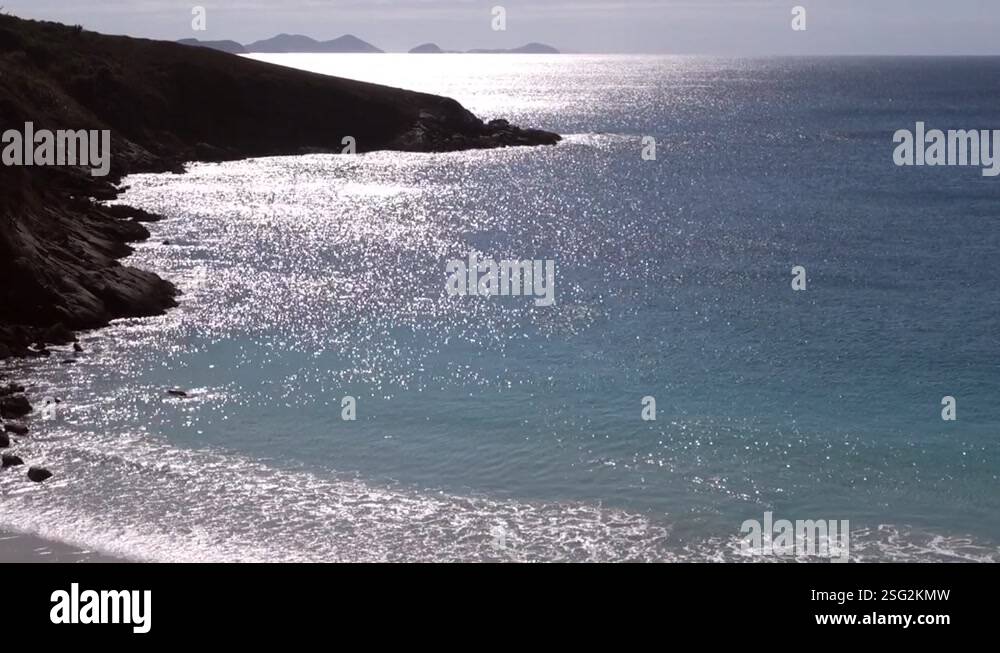 morning sun rays reflecting on sea surface at mountain bay. Aerial ...