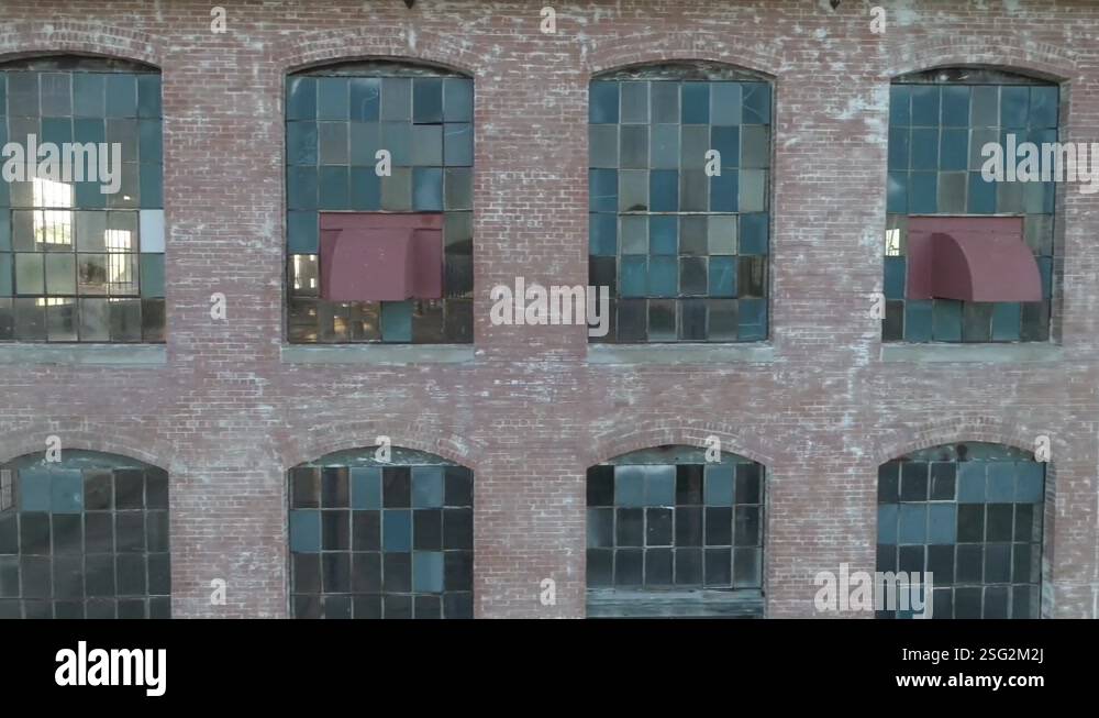 Panning by old windows of an abandoned cotton mill during sunrise as ...