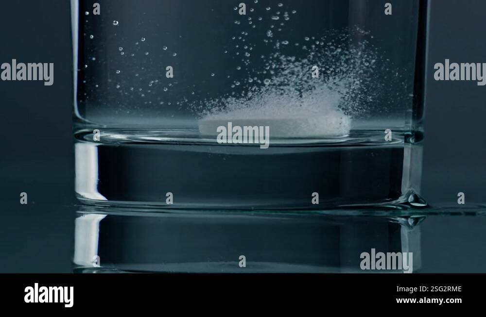 Effervescent drug falling glass bottom closeup. White tablet dissolving ...