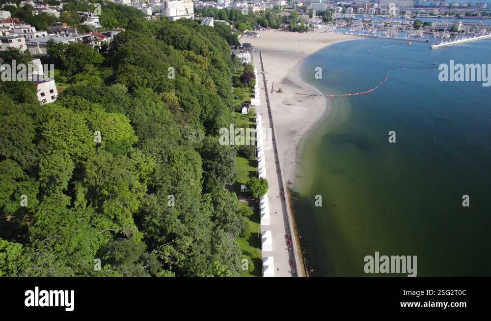 Reveal of a seaside city. Long embankment beside sea beach to protect ...