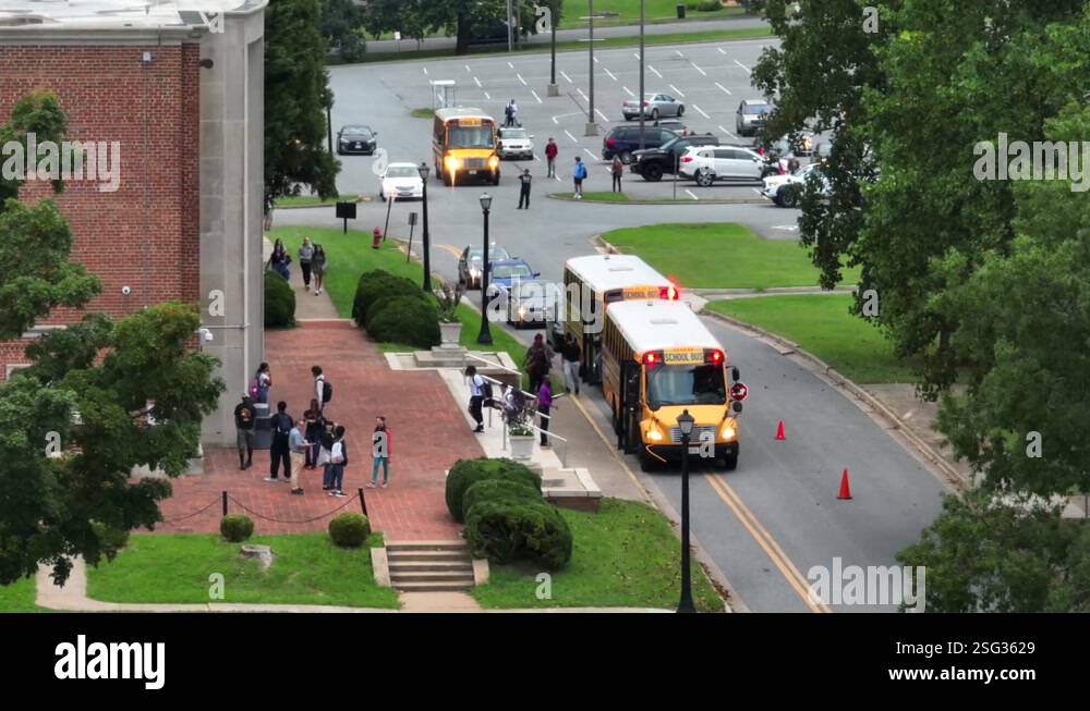 Students arrive at school building. Bus with flashing lights for safety ...