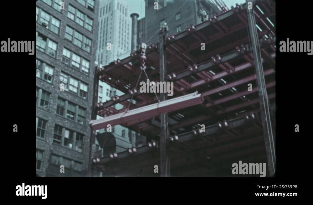 1960s: Crane lifts I-Beam up side of building. Shovel crane dumps ...