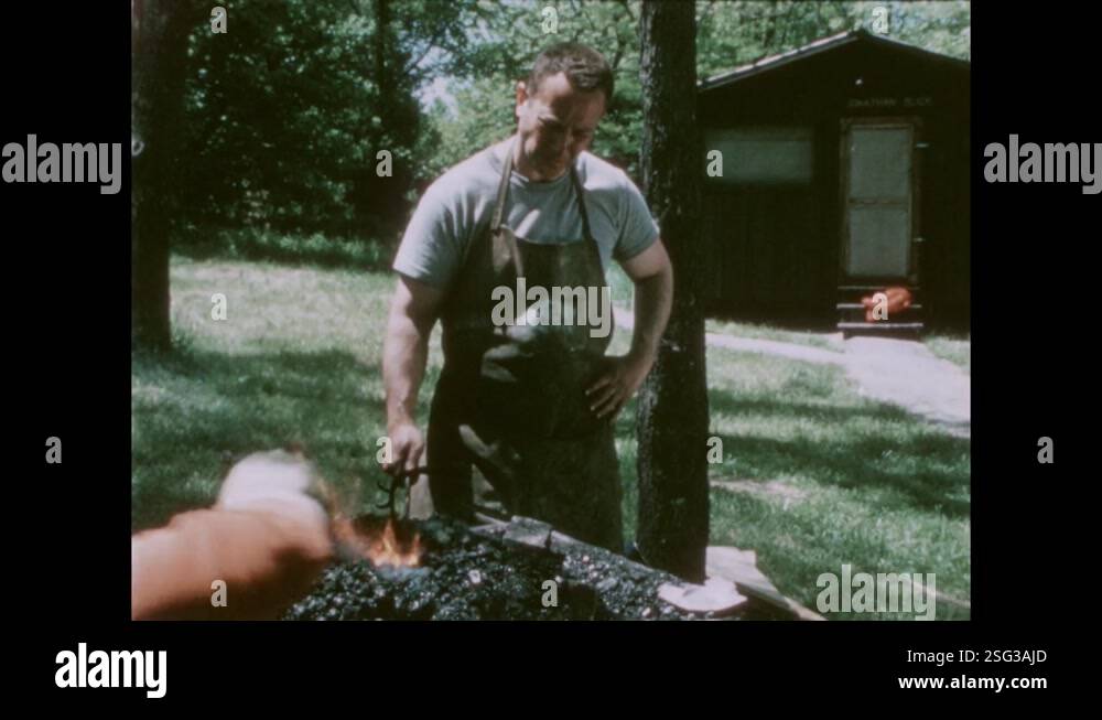 1970s: tongs hold hot metal ring on bench. Ashes on metal anvil ...