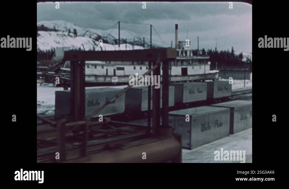 1970s: steam boat and cargo on train by dock. White Pass and Yukon ...