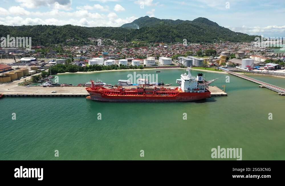 Green, orange, yellow, white cargo ship docking at the Port Panjang ...