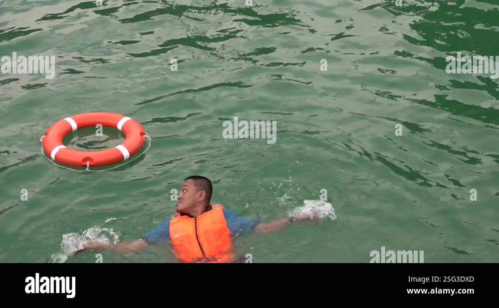 Man wearing a life jacket in a swimming pool, swims to a life jacket ...