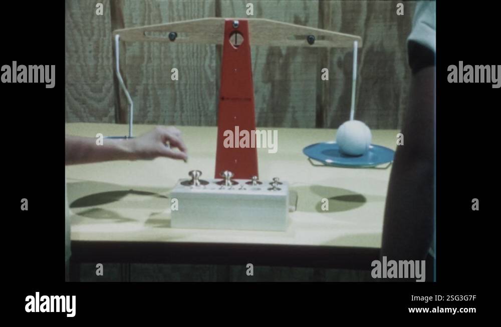 1970s: Hand puts weight on scale. Close up, scale moving. Balanced ...