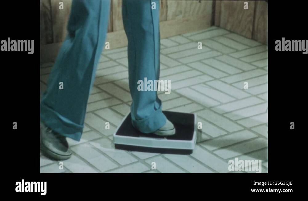 1970s: Feet on scale, step off. Close up of boy. Feet get on scale ...