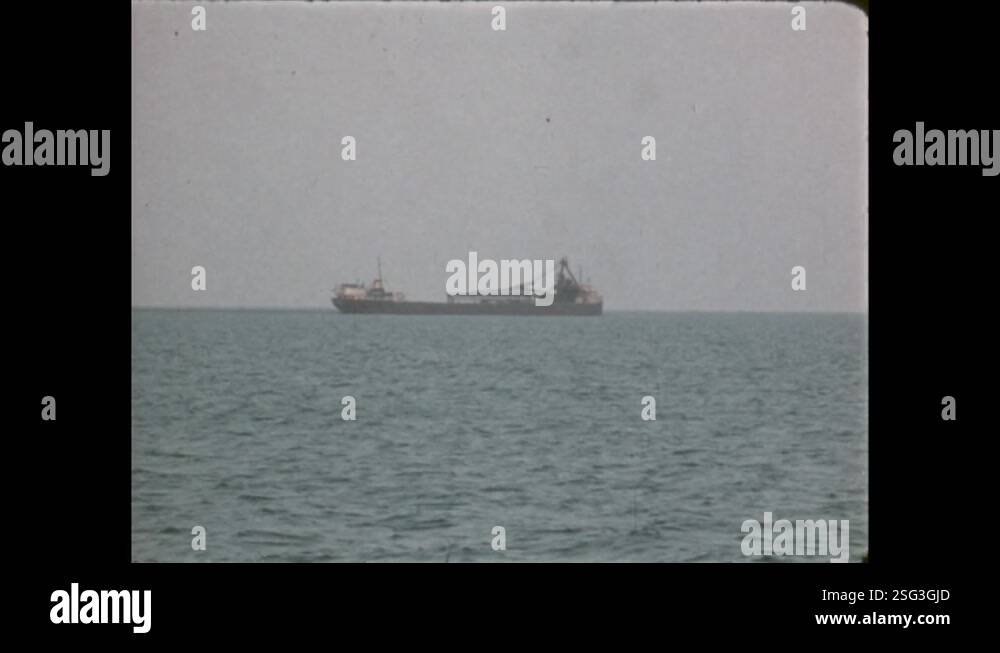 1970s: Powder pouring from chute. Long shot, ship at sea. Ship moving ...