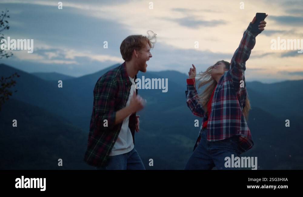 Fun family celebrate dance fun in dusk mountains. Young couple move ...