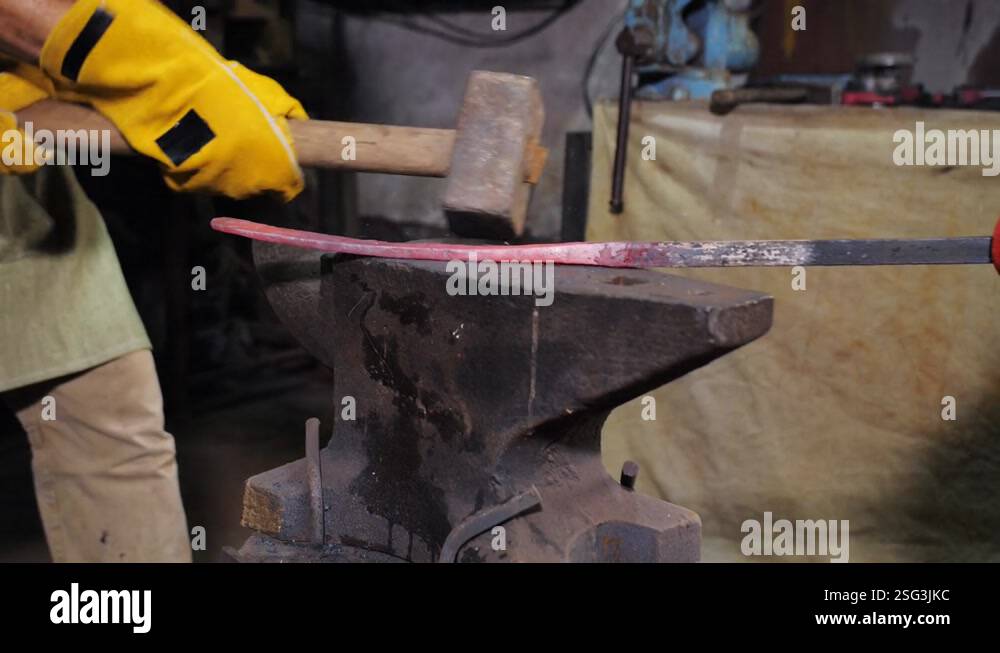 Close-up of a blacksmith hitting a red-hot metal billet on an anvil in ...