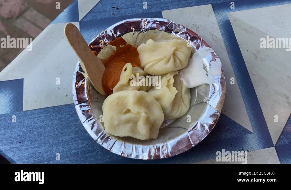 Multiple Momo being served in a paper plate with spicy Schezwan sauce ...