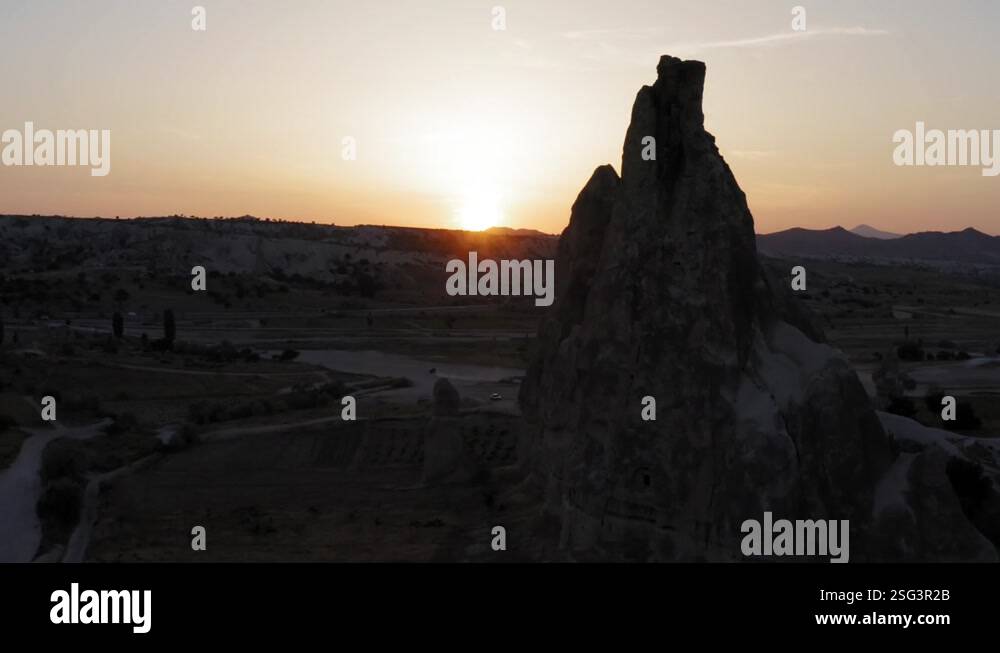Flying drone down next to fairy chimney rock formation as sun sets ...