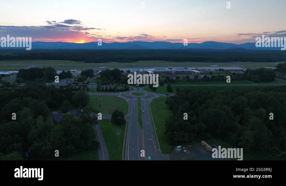 Rising aerial of airport runway at night. Sunset view with mountains ...