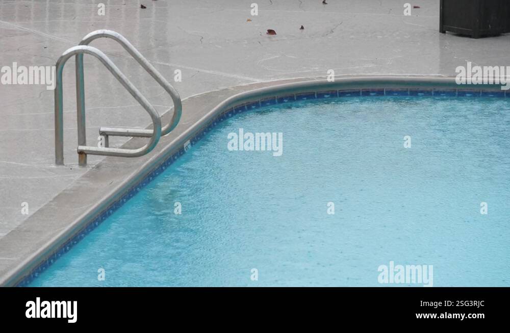 Rain drops falling on water of swimming pool, rainy in California motel ...