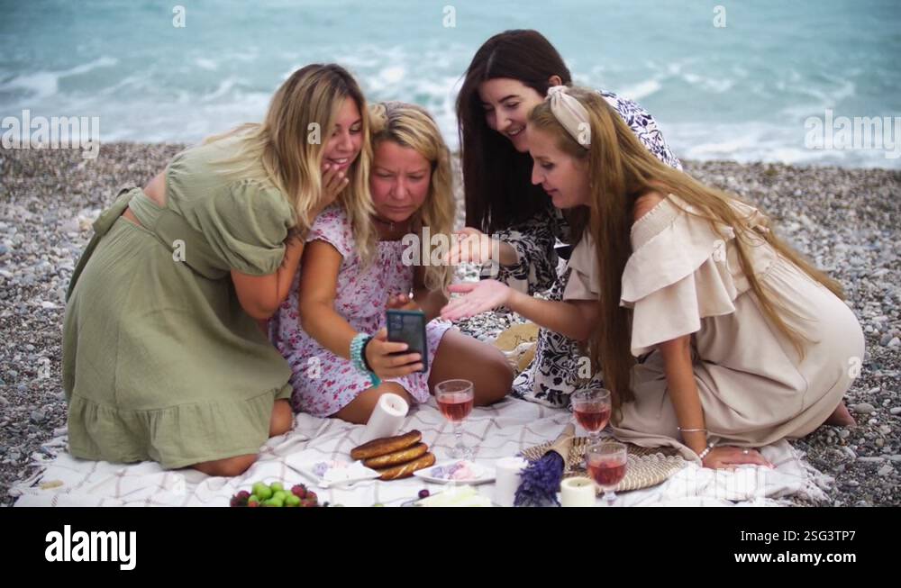 Four women having chilling on the beach - looking at the pictures on ...