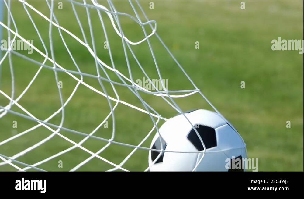 A slow-motion of a soccer football getting into the net on a green ...