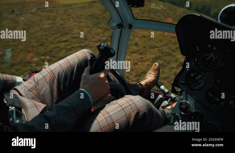 Pilot in a business suit controls a helicopter joystick flying over ...