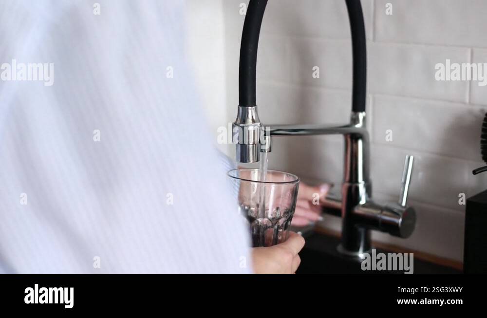 Woman filling drinking glass with tap water on the kitchen. clean ...