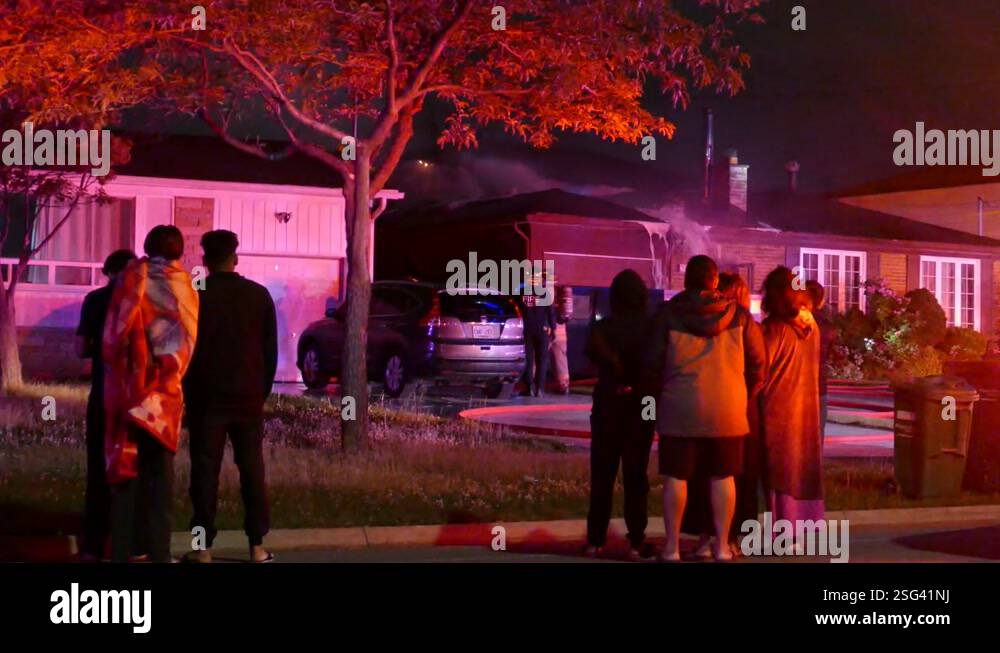 Neighbors watch on as fire crews bring a house fire under control and ...