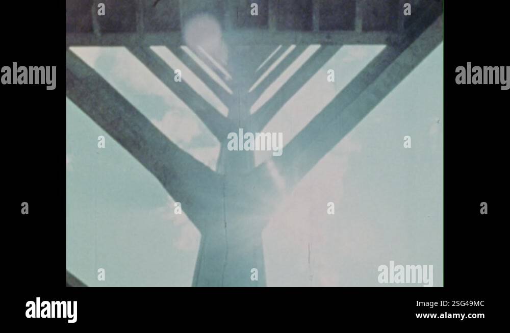 1980s: Buildings in cityscape. People waiting, sitting at bus stop. Bus ...