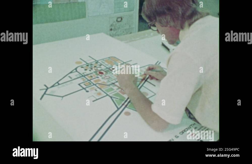 1980s: Man looking at city map on drafting table. Hands drawing on map ...