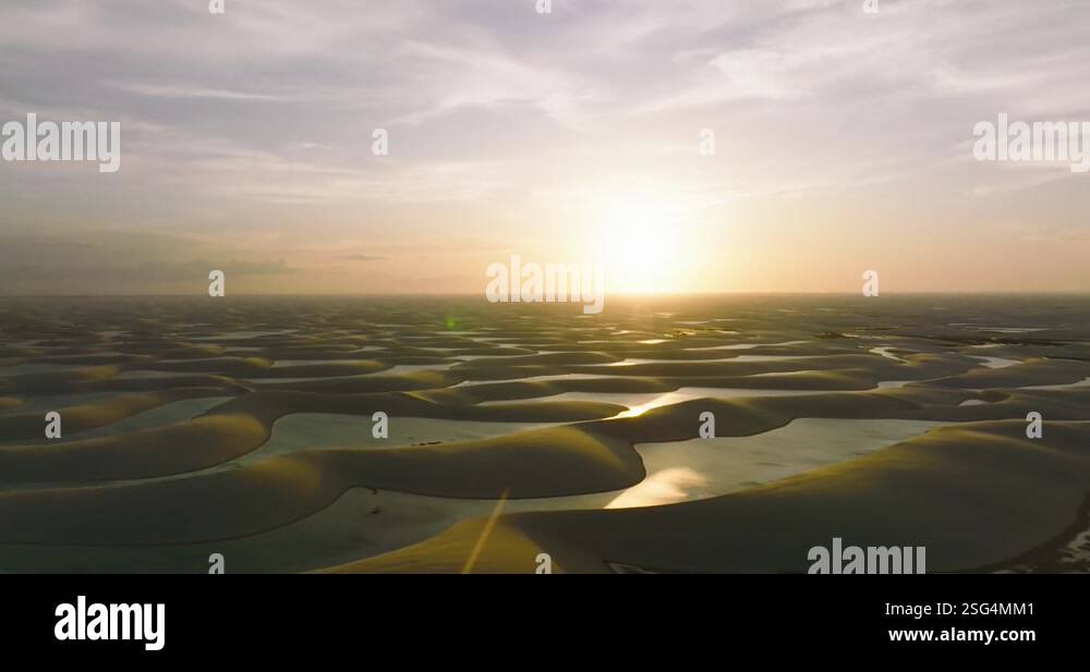 Aerial view of sunlit sand dunes and reflecting rainwater pools, in ...
