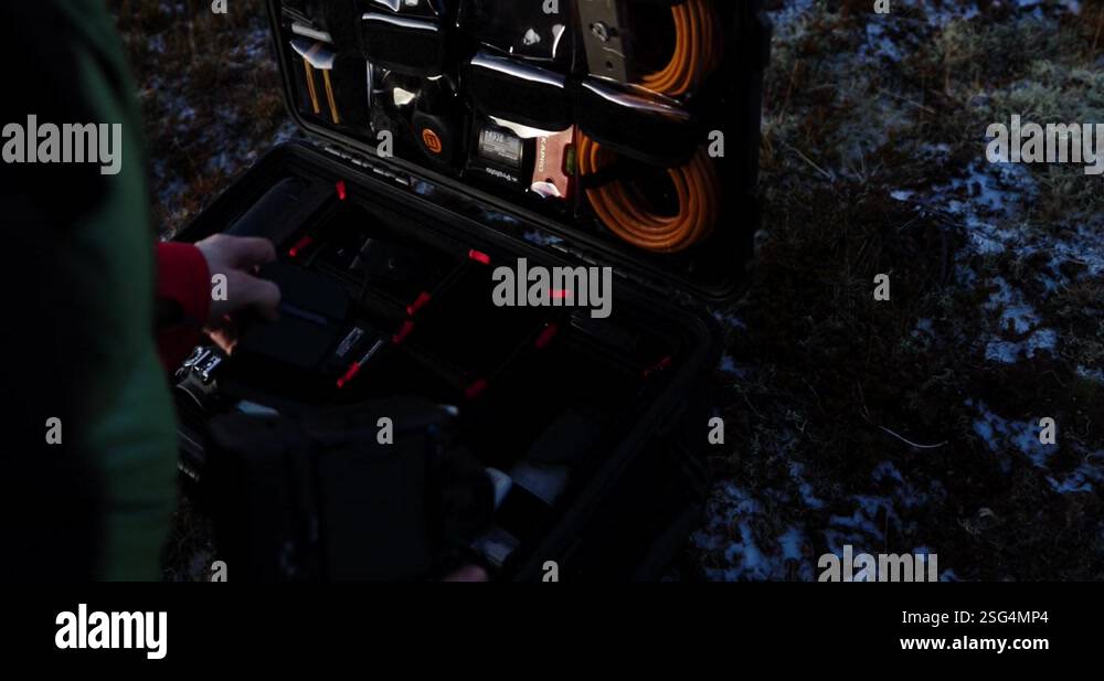 Man taking out large tele lens to put on camera from hard flight case ...