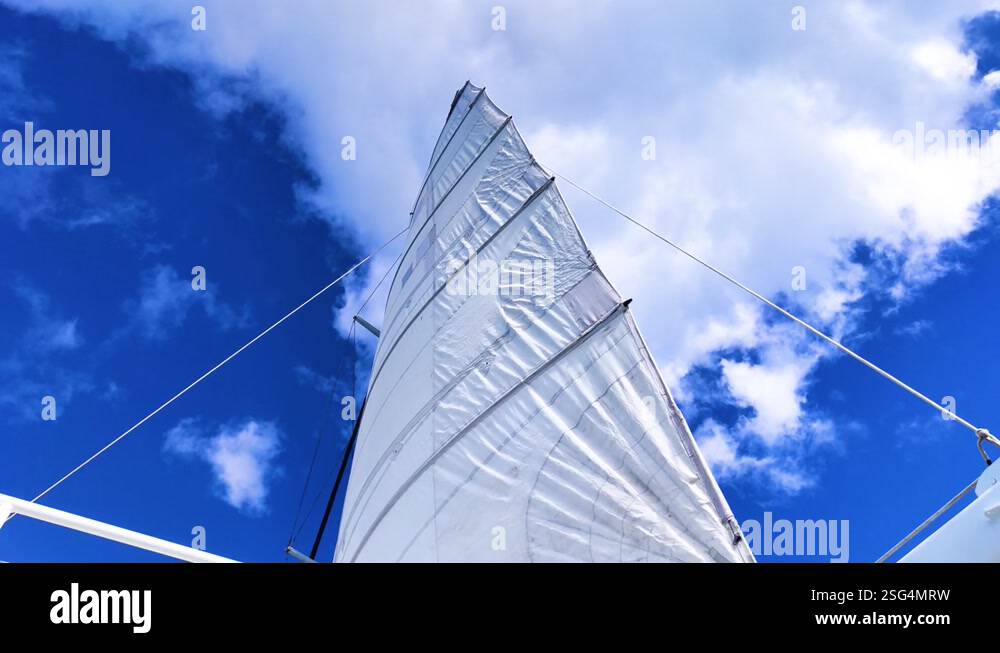 Raising the main sail of a sailing boat with the skies straight above ...