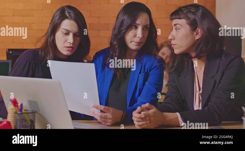 Female executive boss showing documents to young women employees in ...