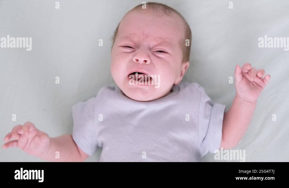 Dissatisfied, crying, upset, sad Newborn baby boy lying in nursery in ...