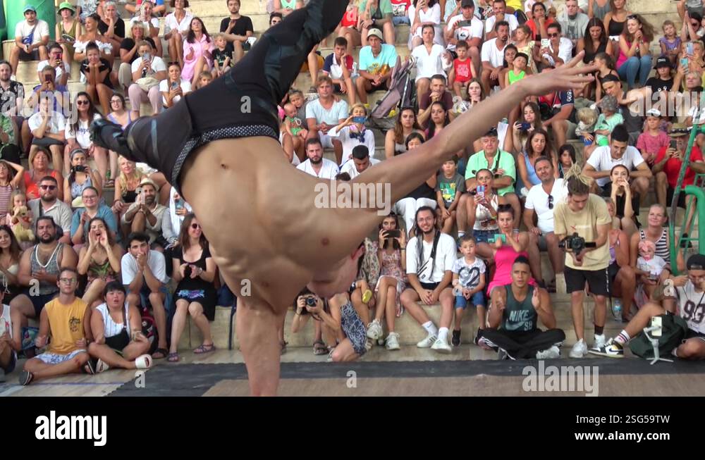 Zoom in belly of an acrobat on bars performing in front of audience ...