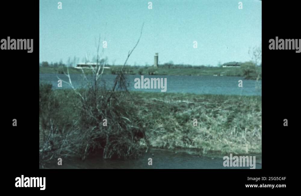 1950s: Pan across river to small dam. Exterior of water treatment plant ...